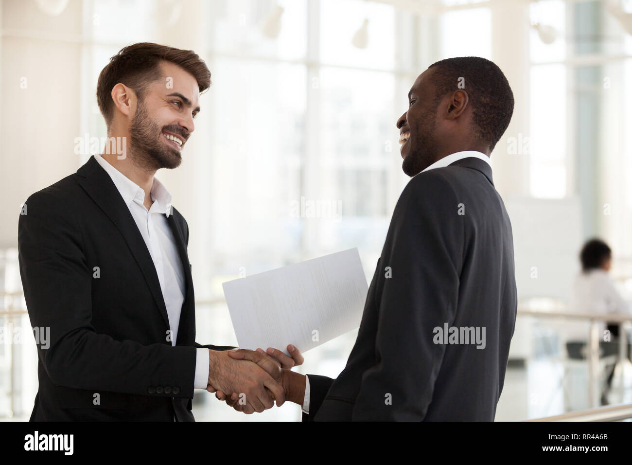 Positive diverse businessmen shaking hands before negotiating Stock ...