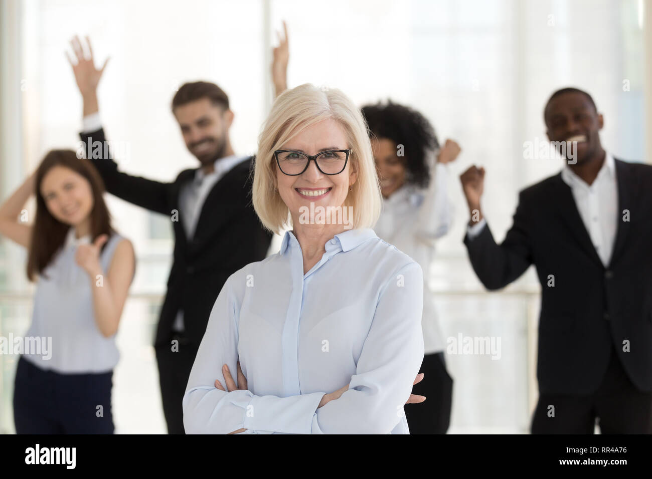 Aged confident team leader with coworkers posing looking at camera ...