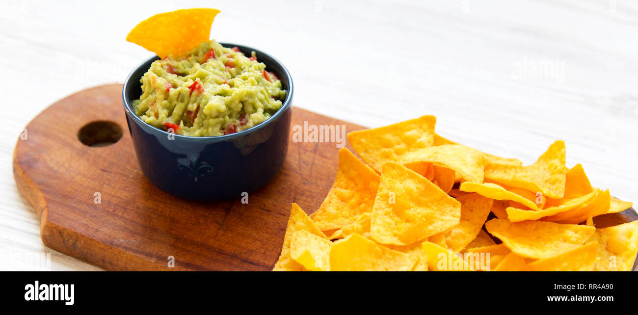 Traditional sauce guacamole with nachos on rustic wooden board on white ...