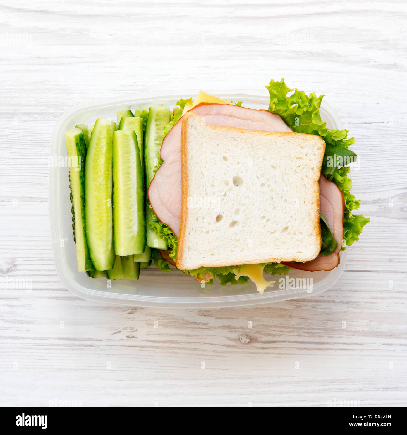 Lunch box with sandwich and vegetables on white wooden surface, top ...