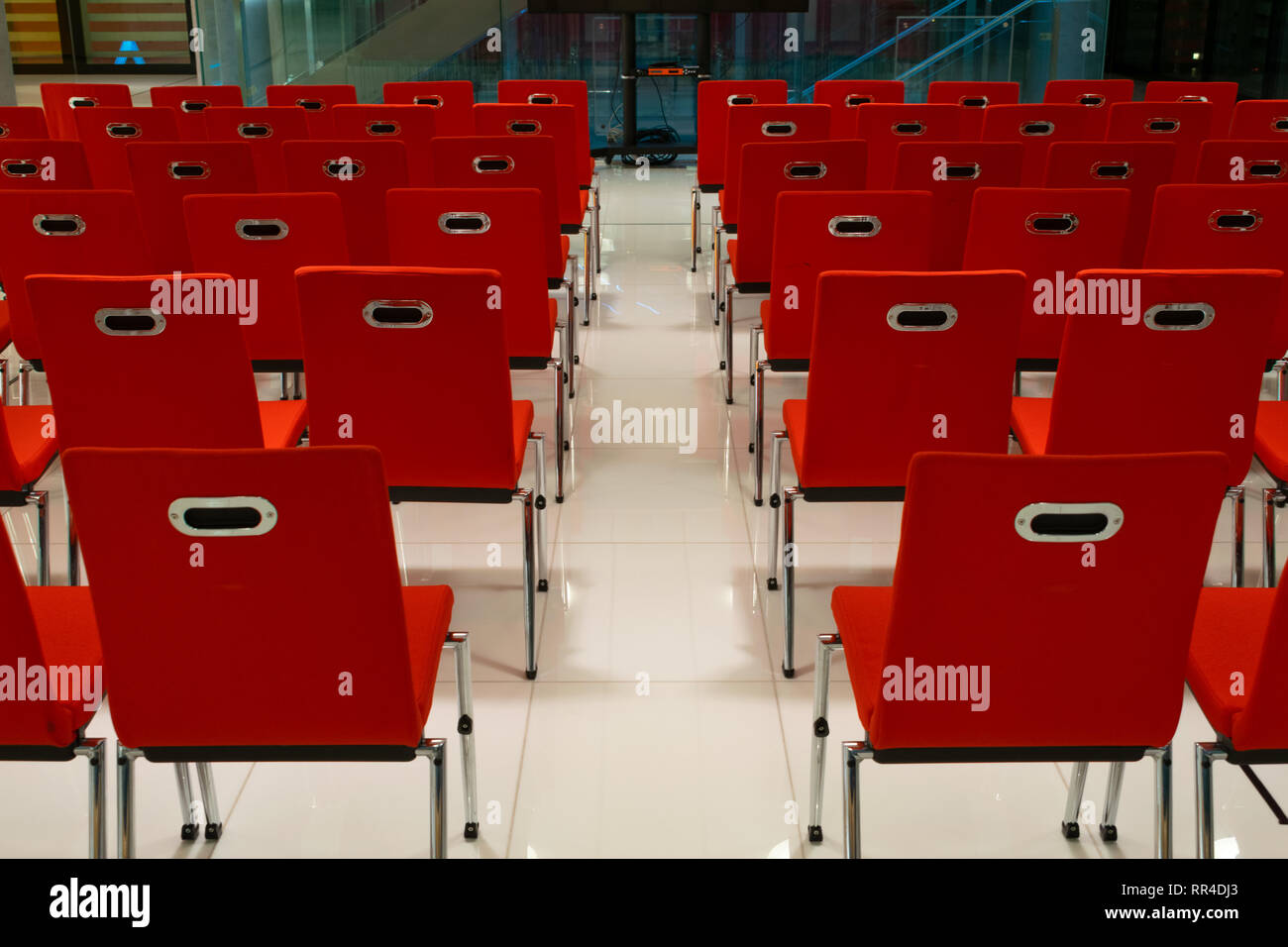 Red chairs aligned in rows in conference room Stock Photo - Alamy