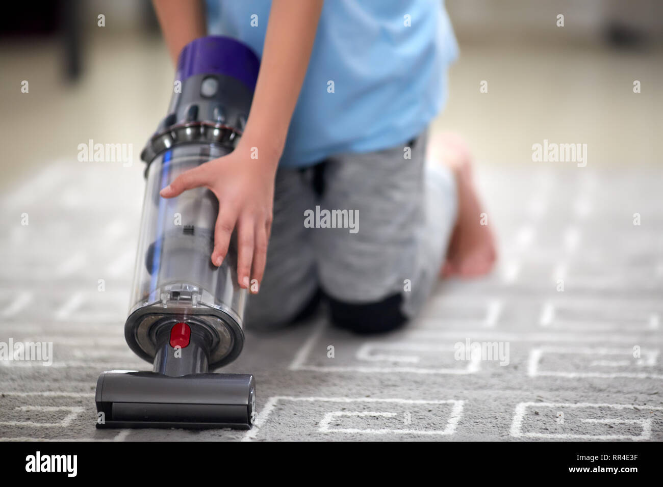 child using a vacuum cleaner while cleaning the carpet in the house ...