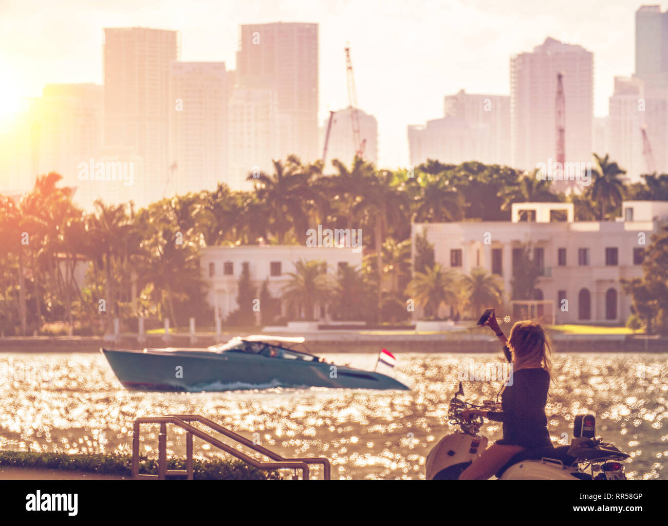 Sunset in Miami with boat and girl taking a selfie on a motor bike ...
