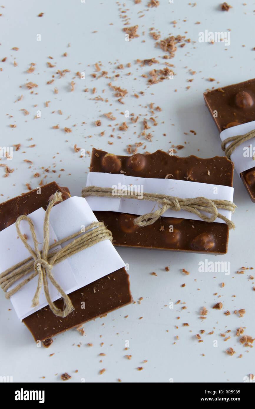 Top view of broken chocolate pieces wrapped in white paper and rustic ...