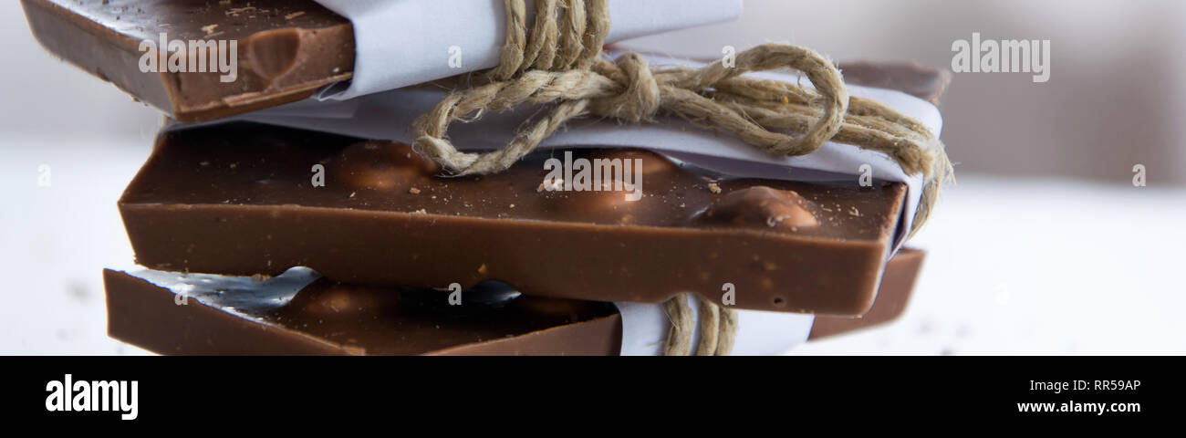Front view of broken chocolate pieces wrapped in white paper and rustic ...