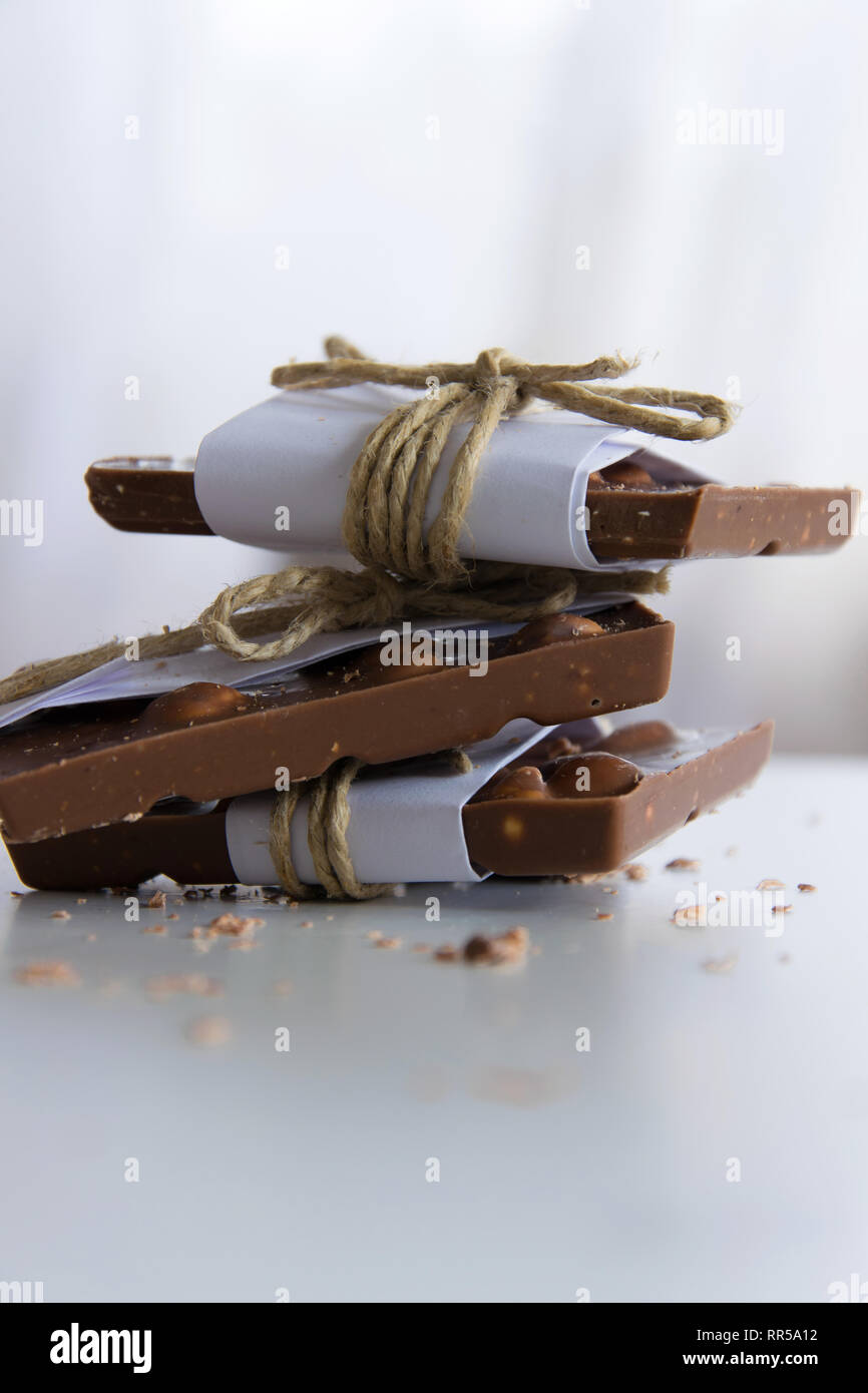 Front view of broken chocolate pieces wrapped in white paper and rustic ...