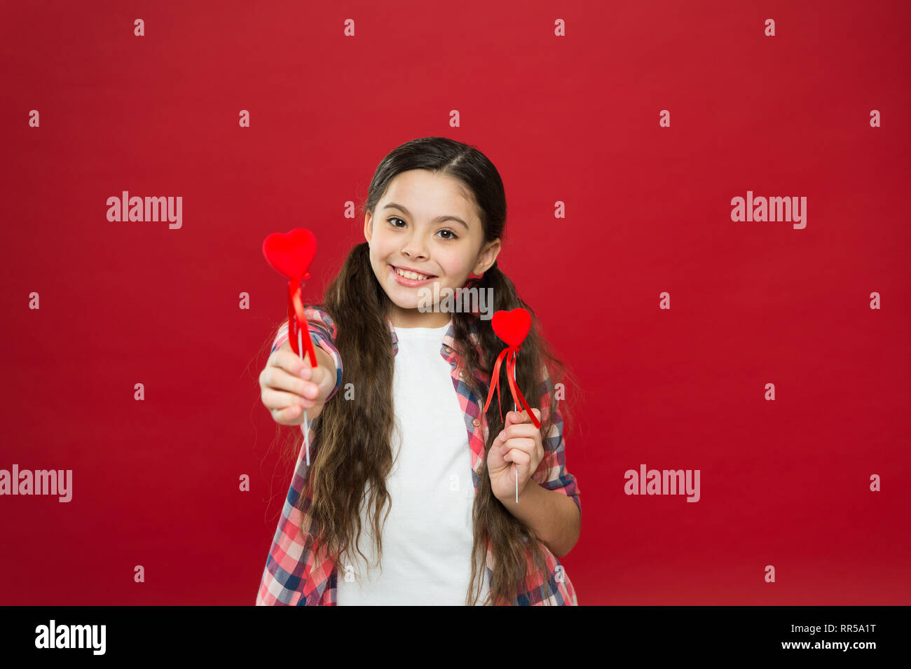 This is a day to say I love you. Small girl giving hearts on sticks ...