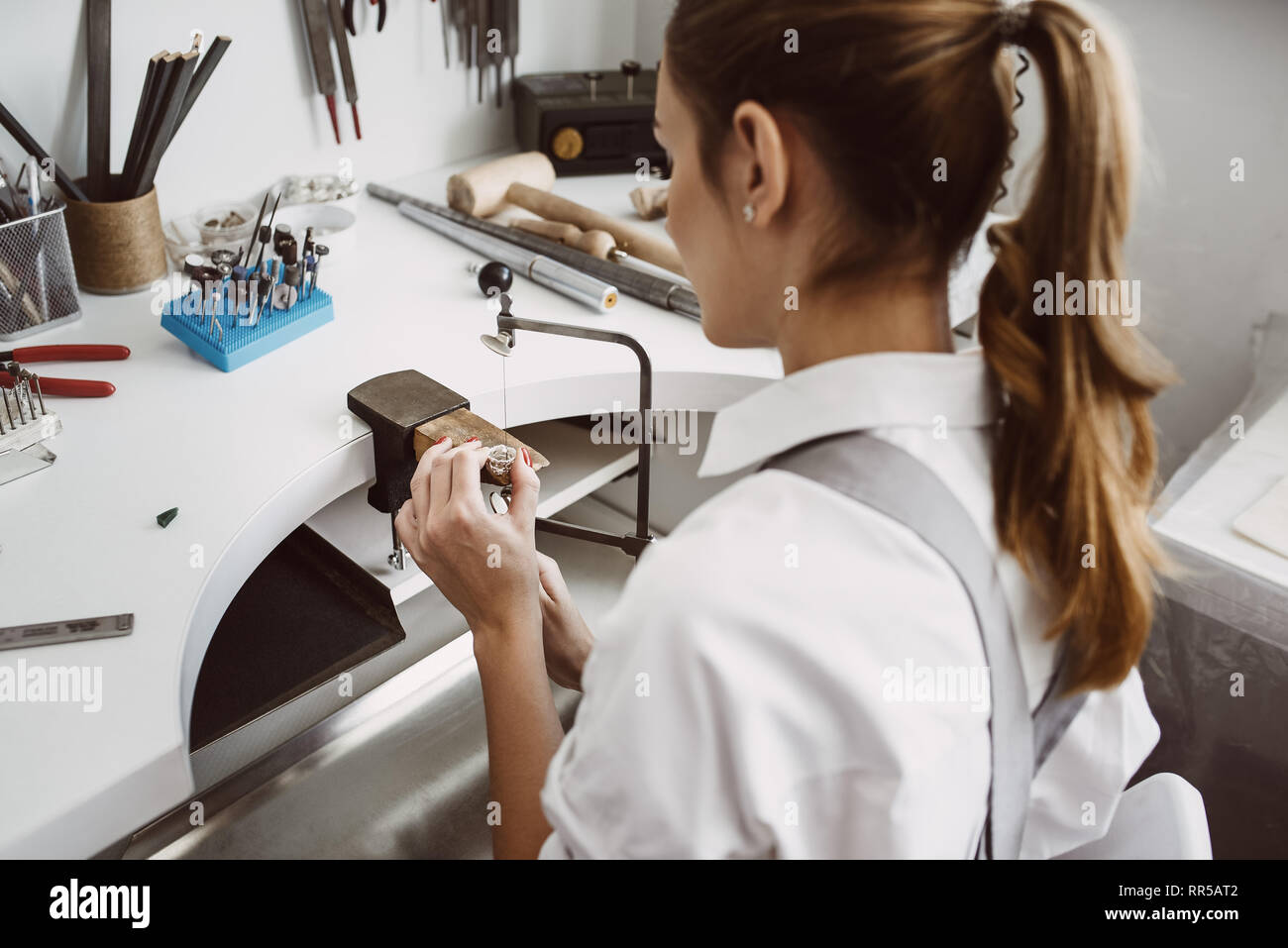 Focused on work. Side view of young female jeweler making a ring at her ...