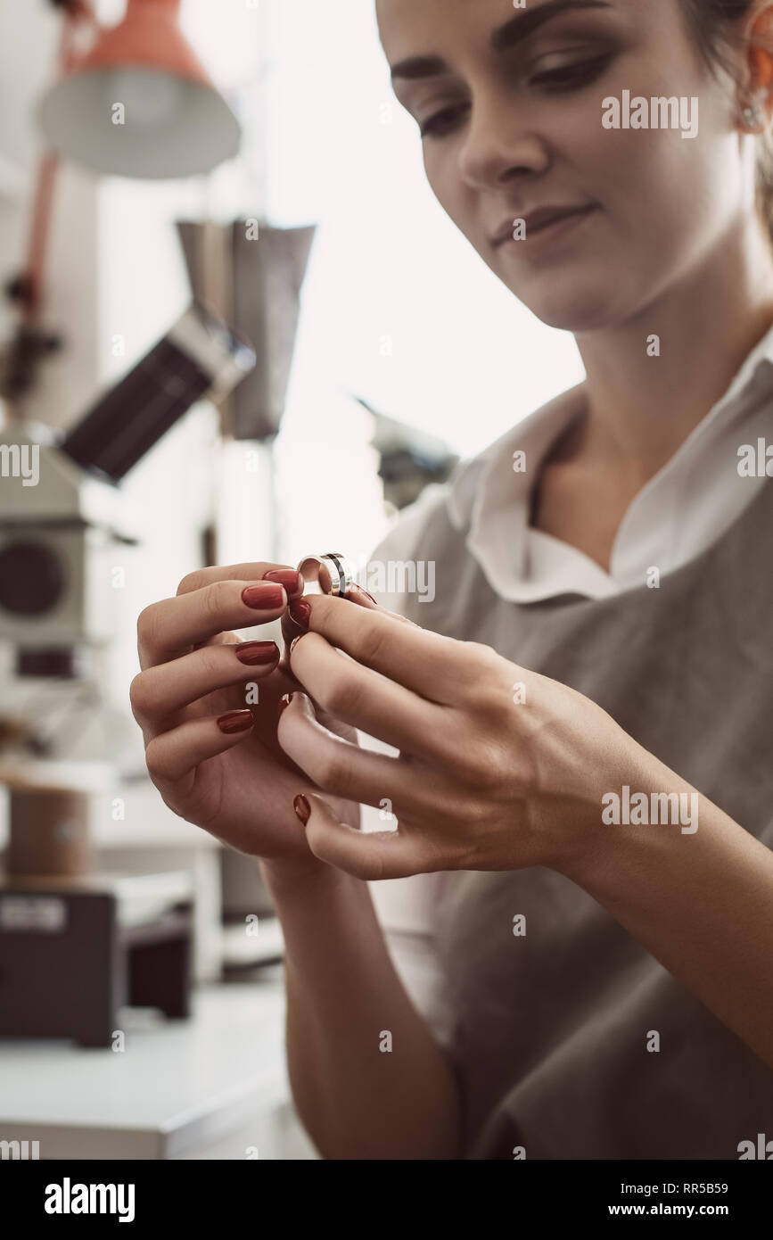 On the way to perfection. Vertical photo of female jeweler examining ...
