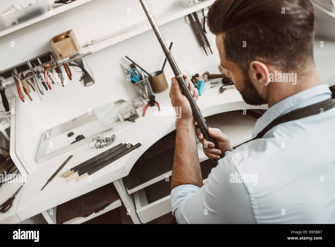 Right instrument. Back view of young male jeweler checking ring size ...