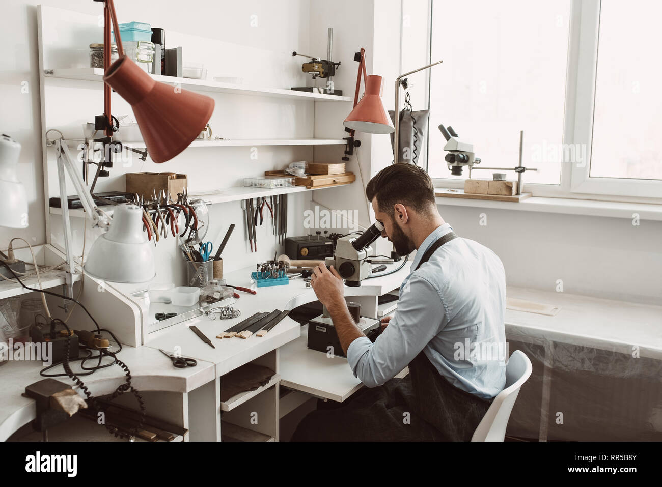 Focused on his job. Side view of a male jeweler looking at the ring ...