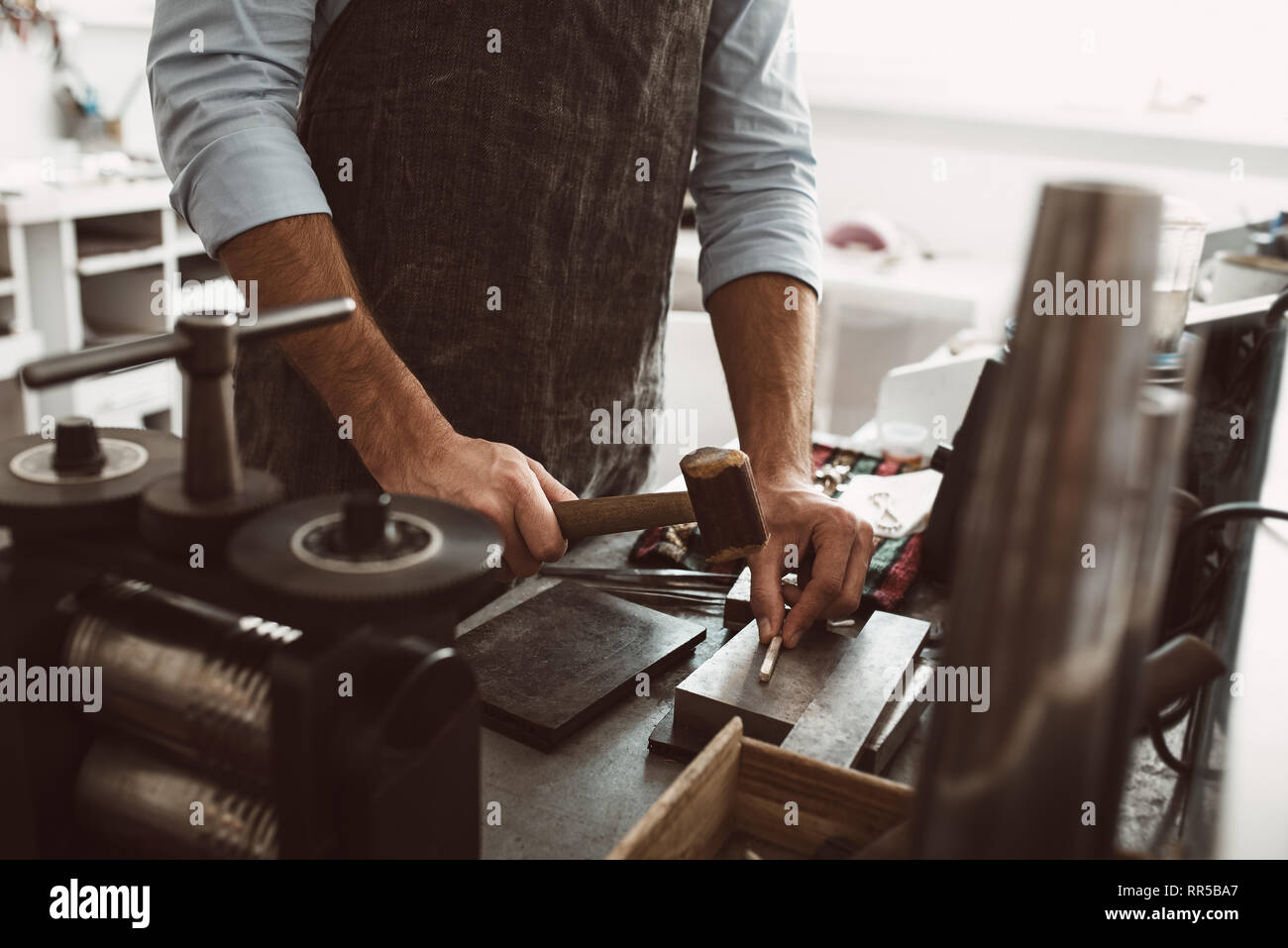 Important stage in the work. Male goldsmith wearing apron making a new ...