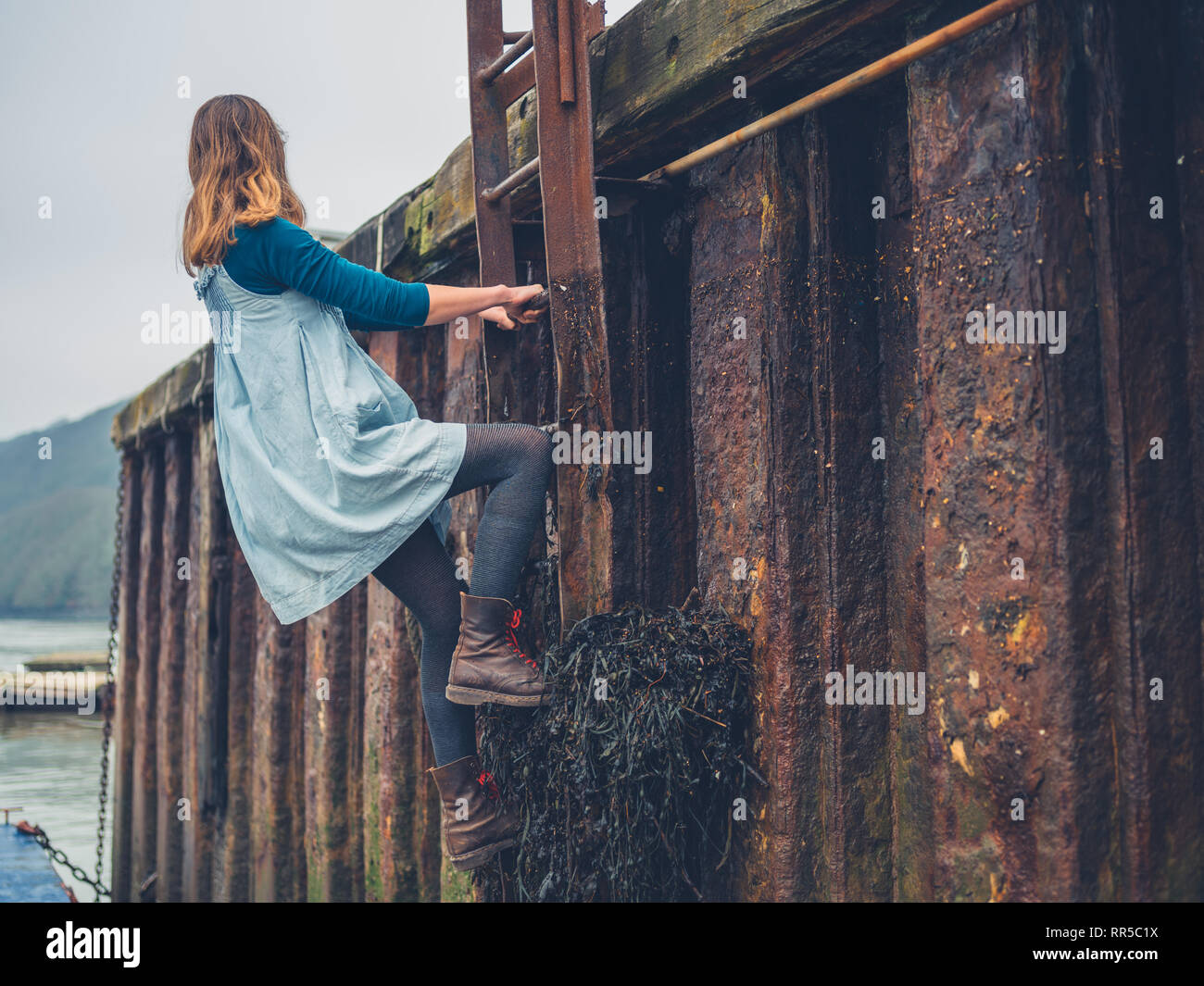 A young woman is hanging from a ladder in a shipyard Stock Photo - Alamy