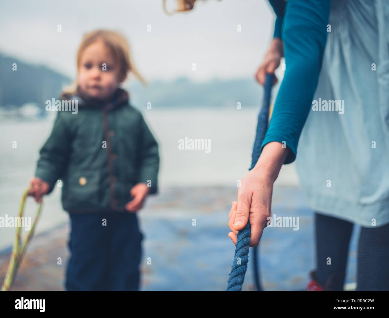A young mother and her toddler are pulling a rope on a jetty Stock ...