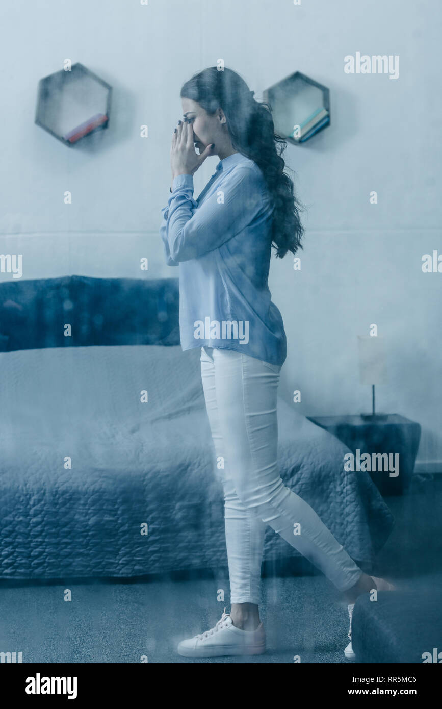 depressed woman covering face with hands and crying at home through ...