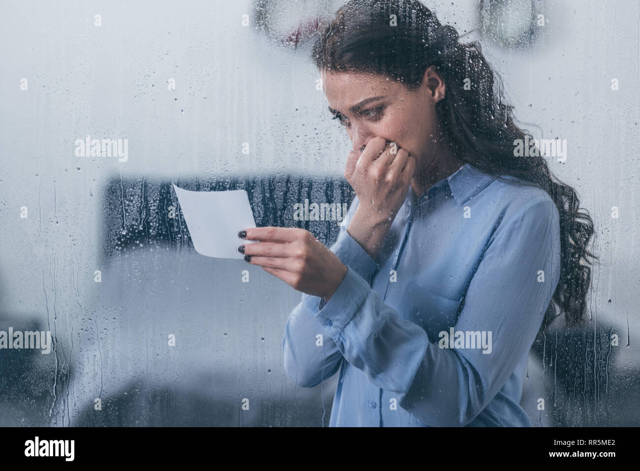 grieving woman holding photograph, covering mouth with hand and crying ...