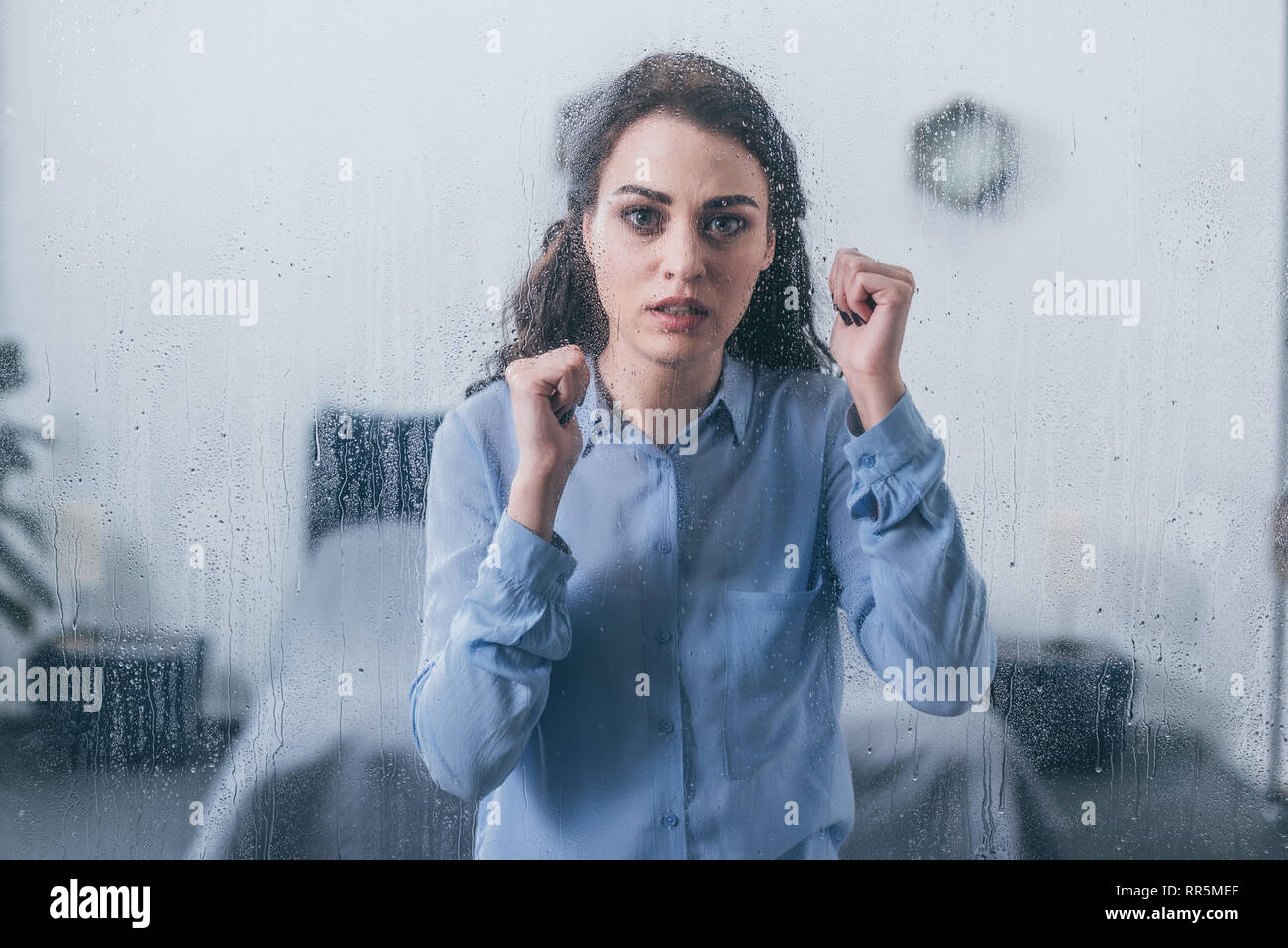 beautiful sad woman with clenched fists looking at camera through ...