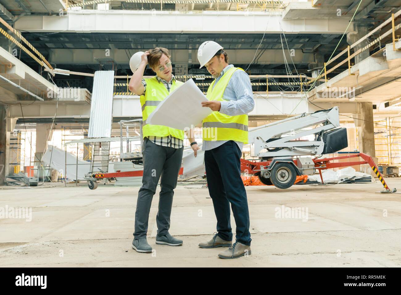 Male building workers working at construction site, builders looking in ...