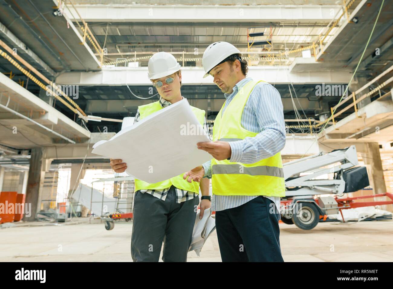 Male building workers working at construction site, builders looking in ...