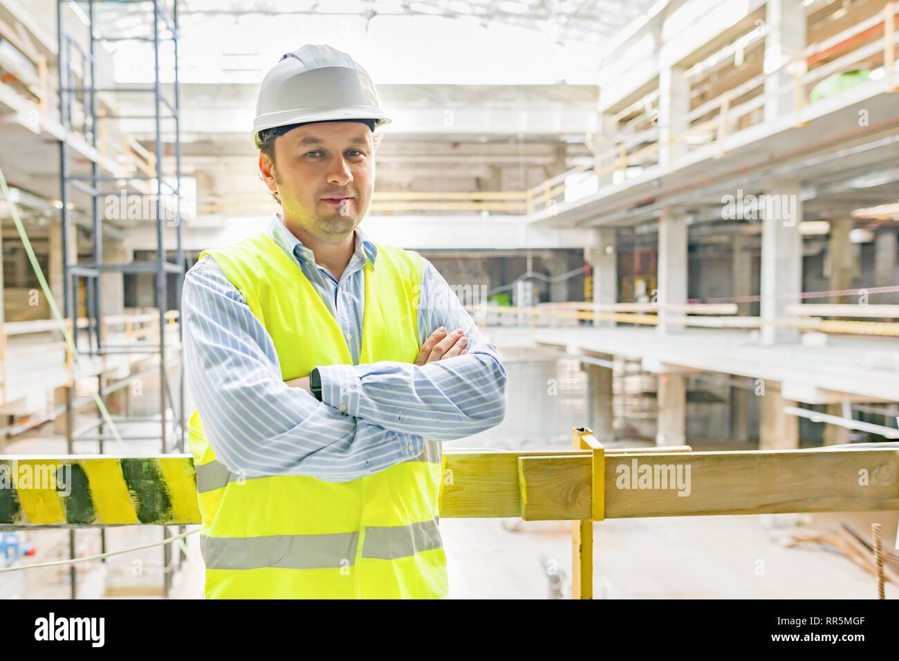 Portrait of confident male builder, manager, engineer with folded hands ...