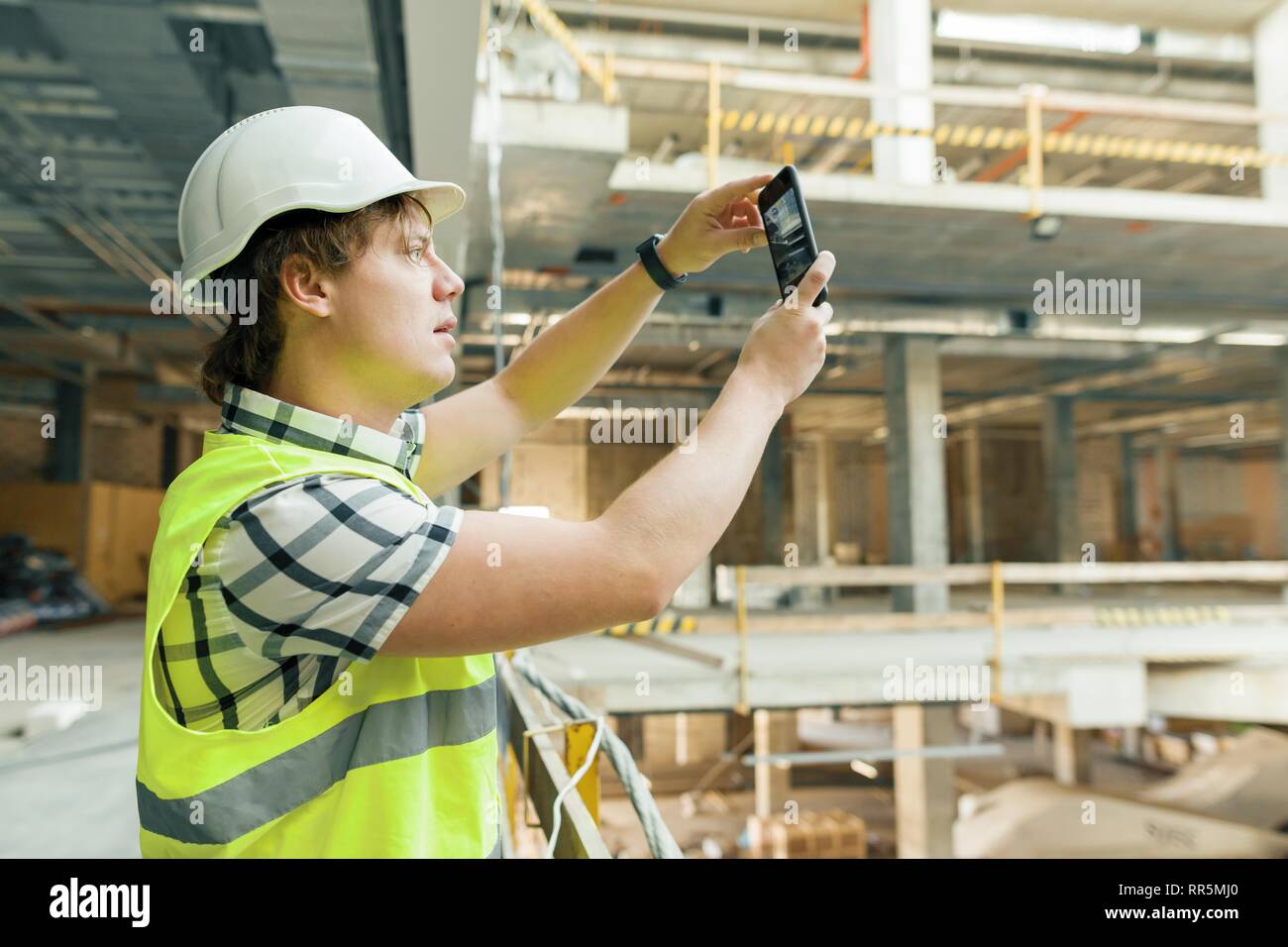 Portrait of male builder, manager, engineer photographing construction ...