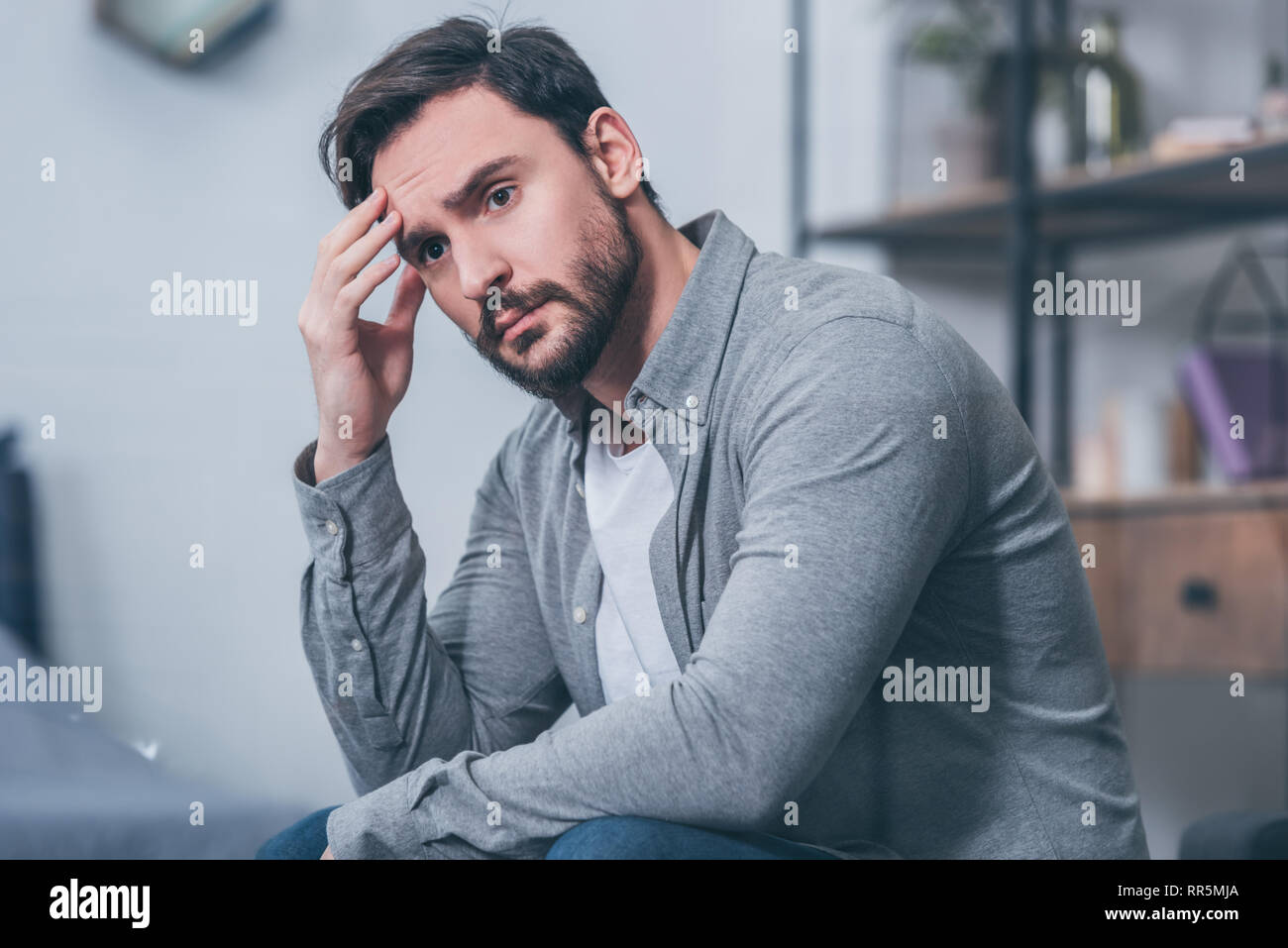 selective focus of handsome upset man sitting, touching face and ...