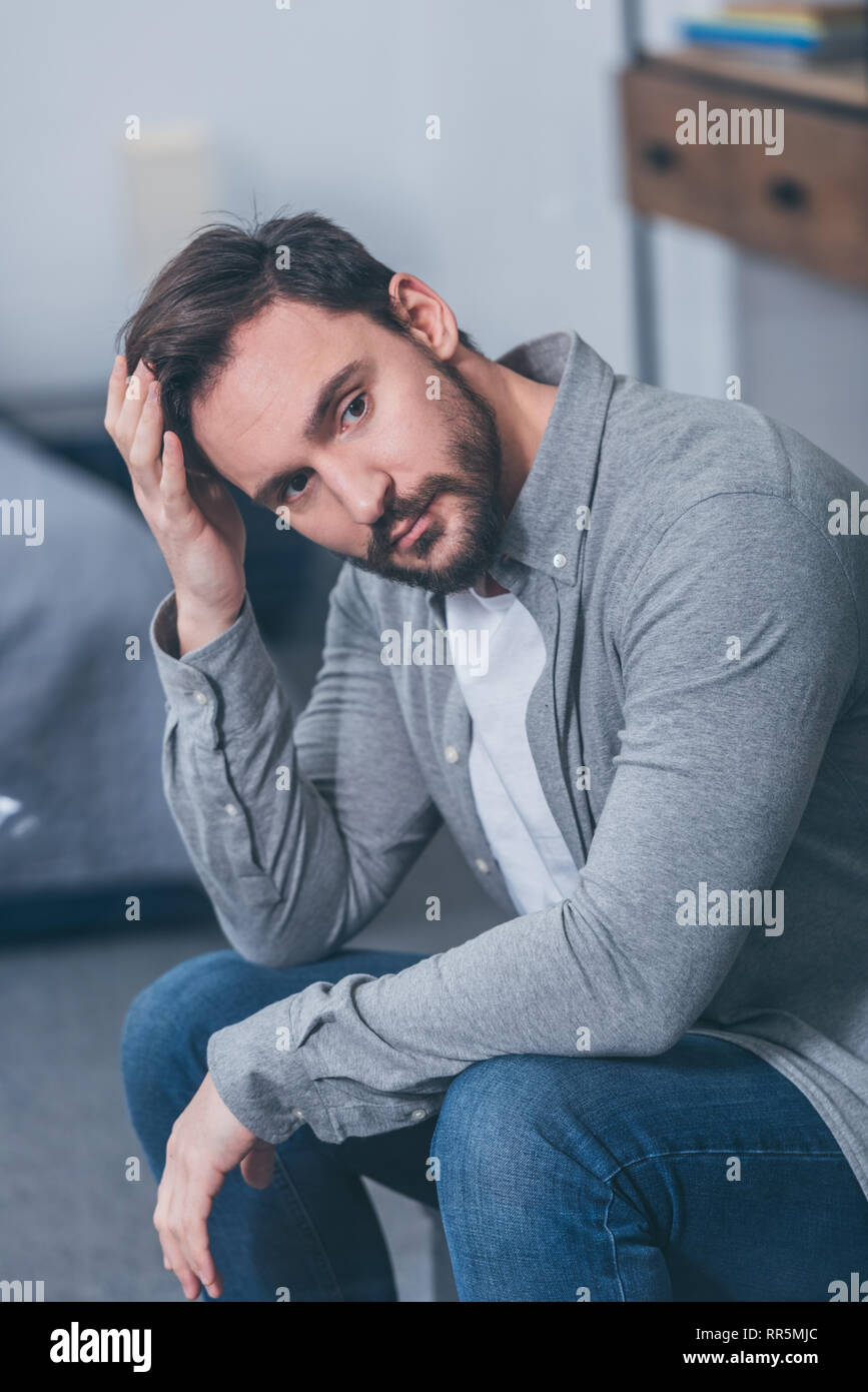 selective focus of handsome upset man sitting, touching face and ...