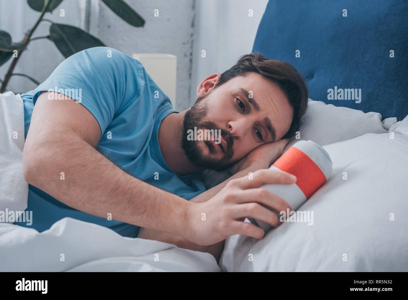 grieving man lying in bed and holding funeral urn Stock Photo - Alamy