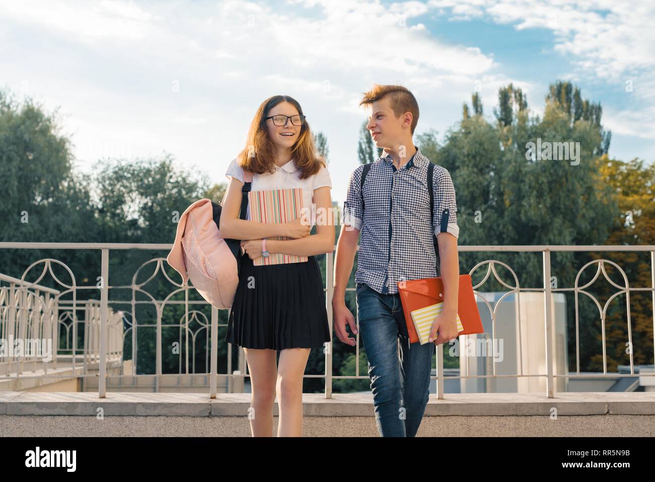 Adolescents students with backpacks, textbooks, go to school. Outdoor ...