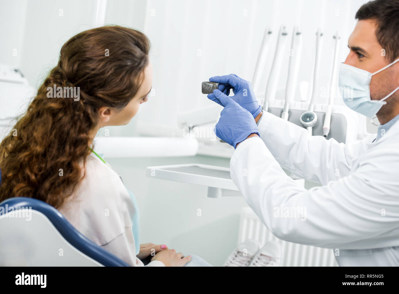 selective focus of dentist in mask pointing with finger at x-ray of ...