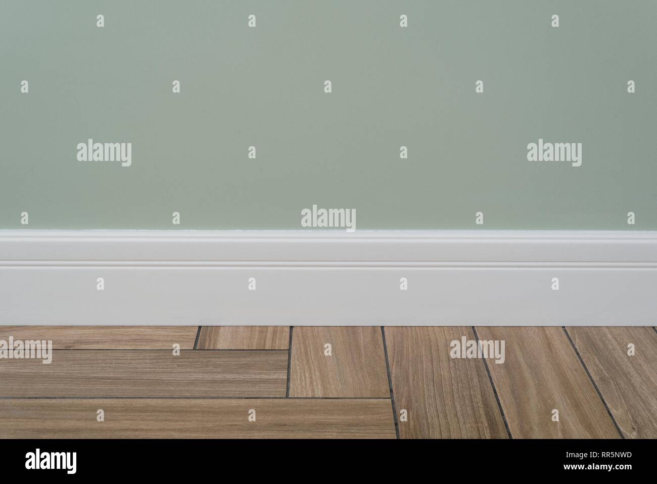 Interior concept. Light green matte wall, white baseboard and tiles ...