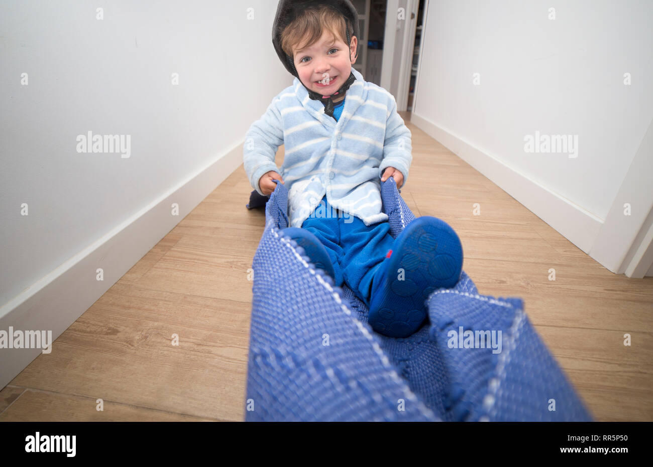 Pulling the carpet through the home corridor with child pilot. Exciting ...