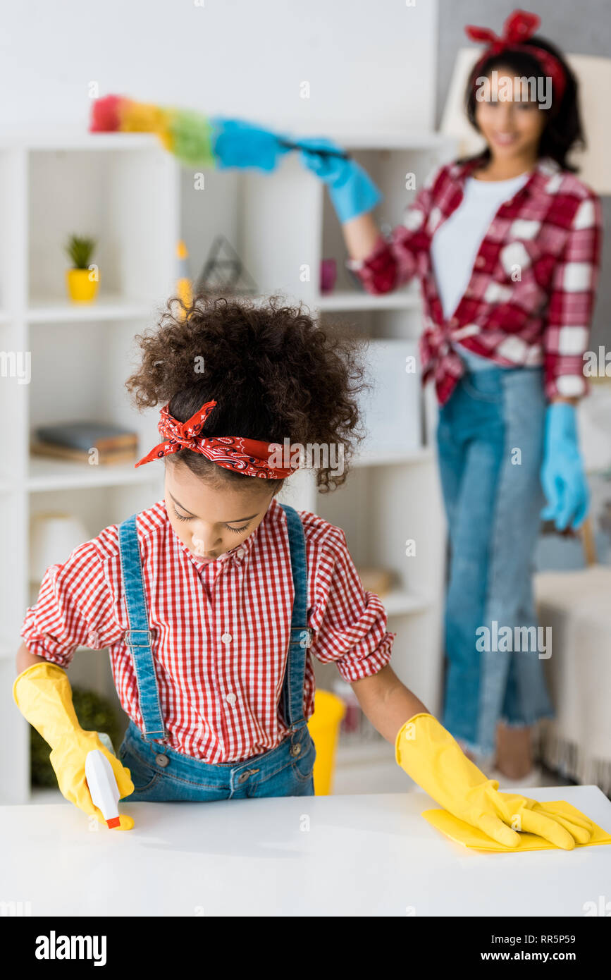 selective focus of cute african american child cleaning table while ...