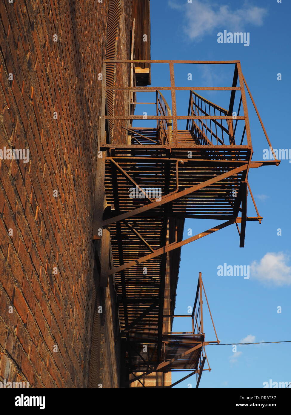 Brick building with fire escape against blue sky Stock Photo - Alamy