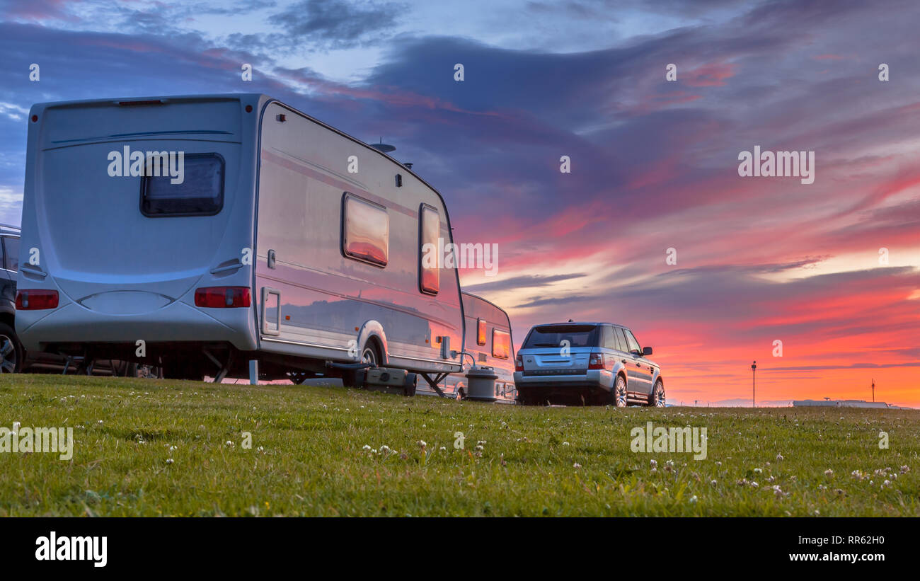 Camping caravans and cars parked on a grassy campground under beautiful ...