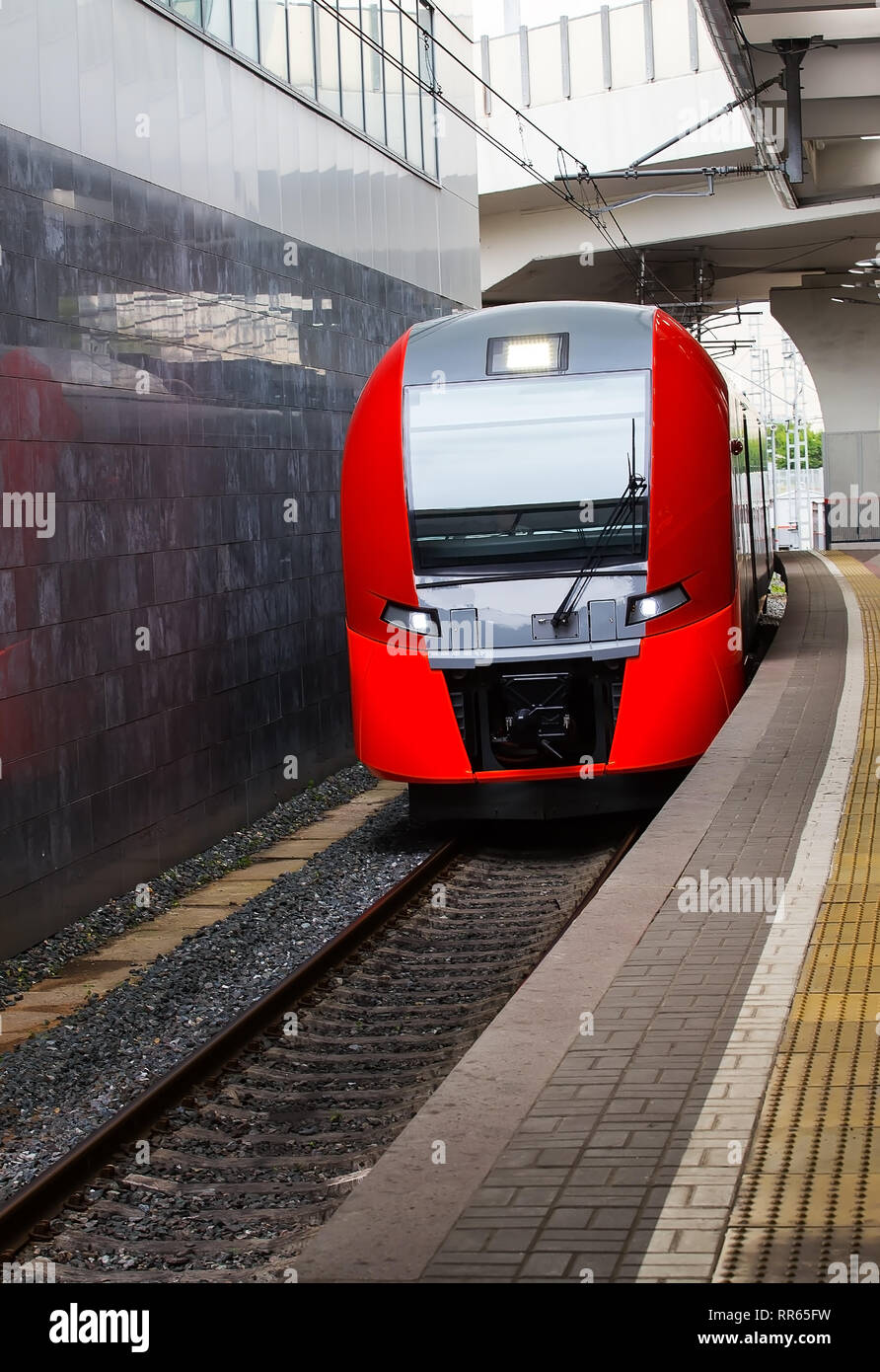 Modern red train approaching the train station Stock Photo - Alamy