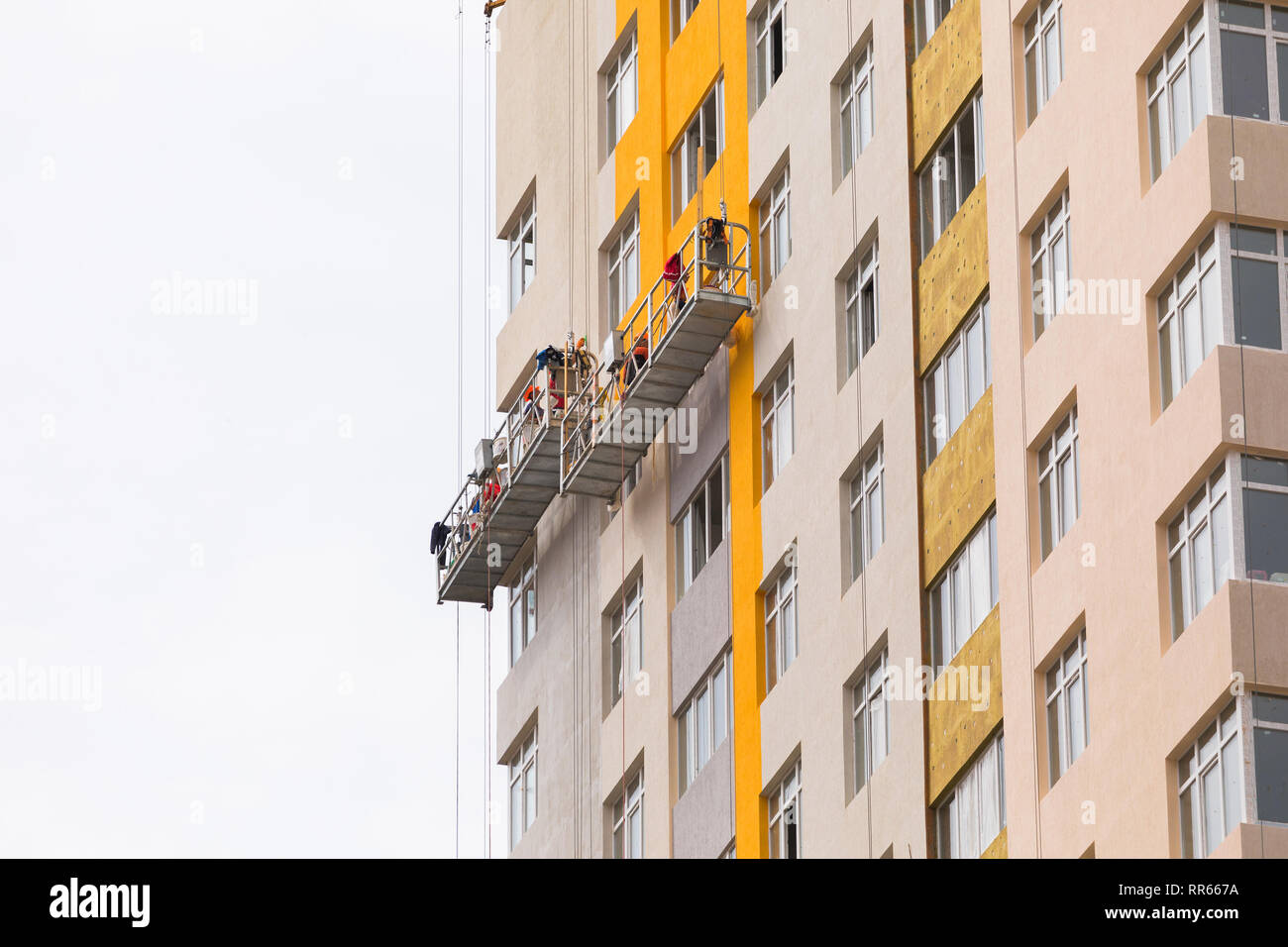 Builders paint the facade of a high-rise residential building Stock ...