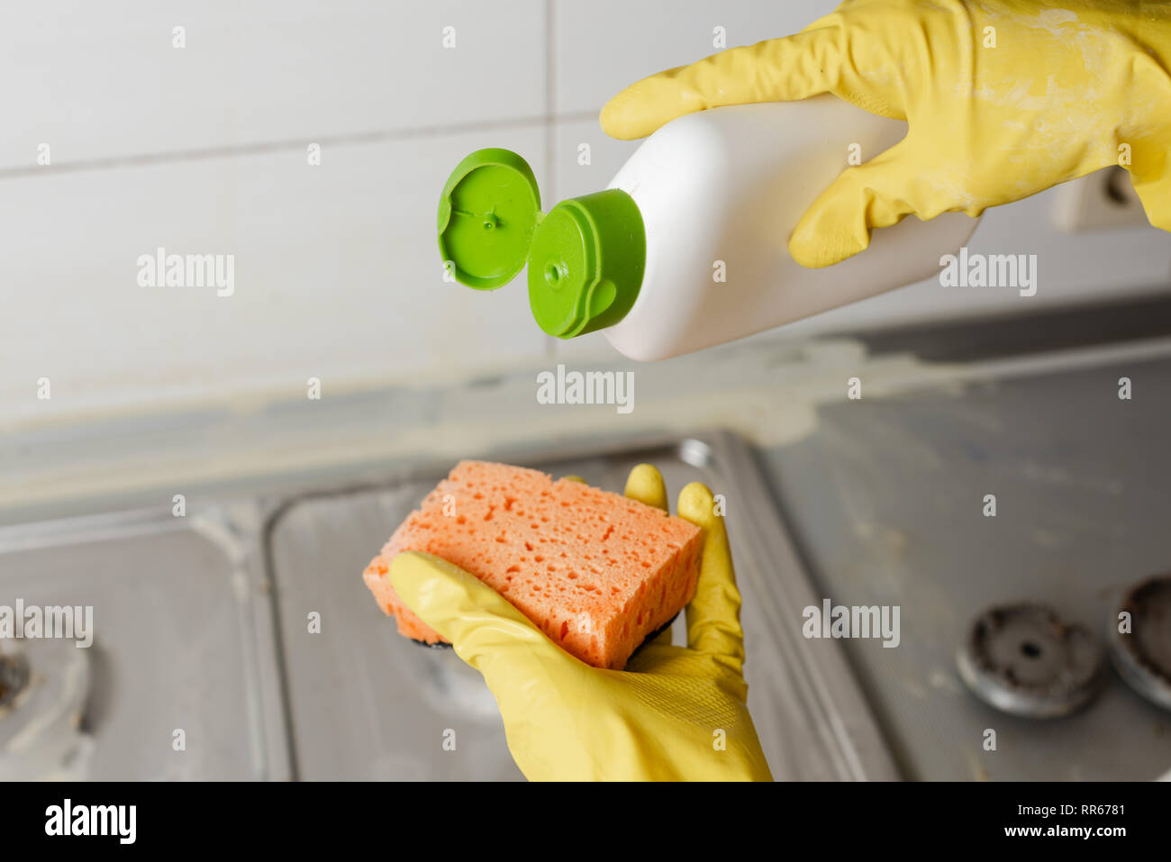Close-up of hands applying liquid soap from cleanser bottle to sponge ...