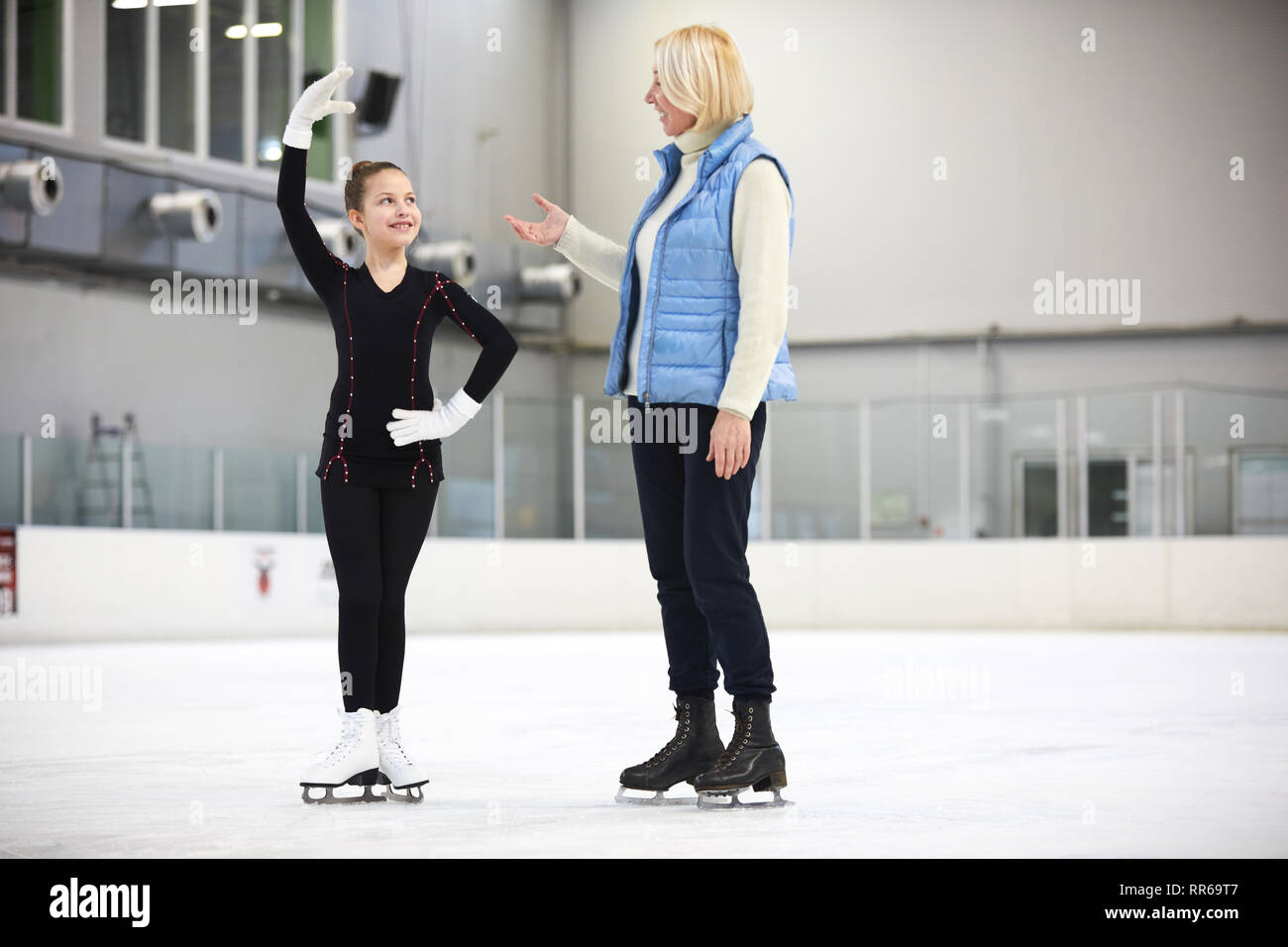 Full length portrait of happy girl figure skating on rink looking at ...
