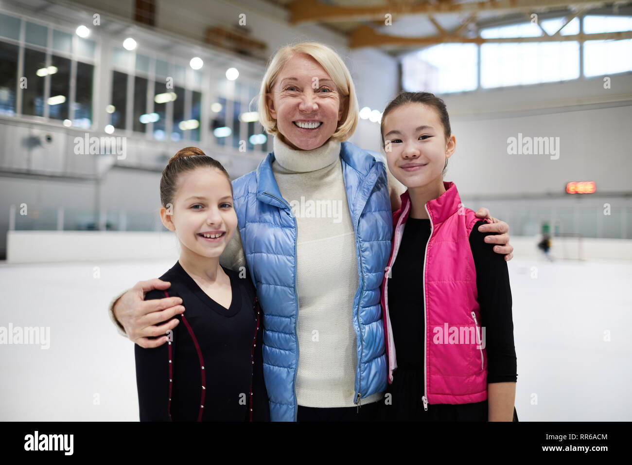 Waist up portrait of mature female coach posing with two girls after ...