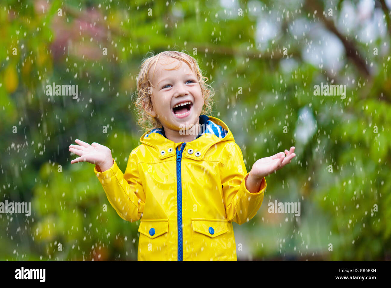 Kids play in autumn rain. Child playing outdoor on rainy day. Little ...