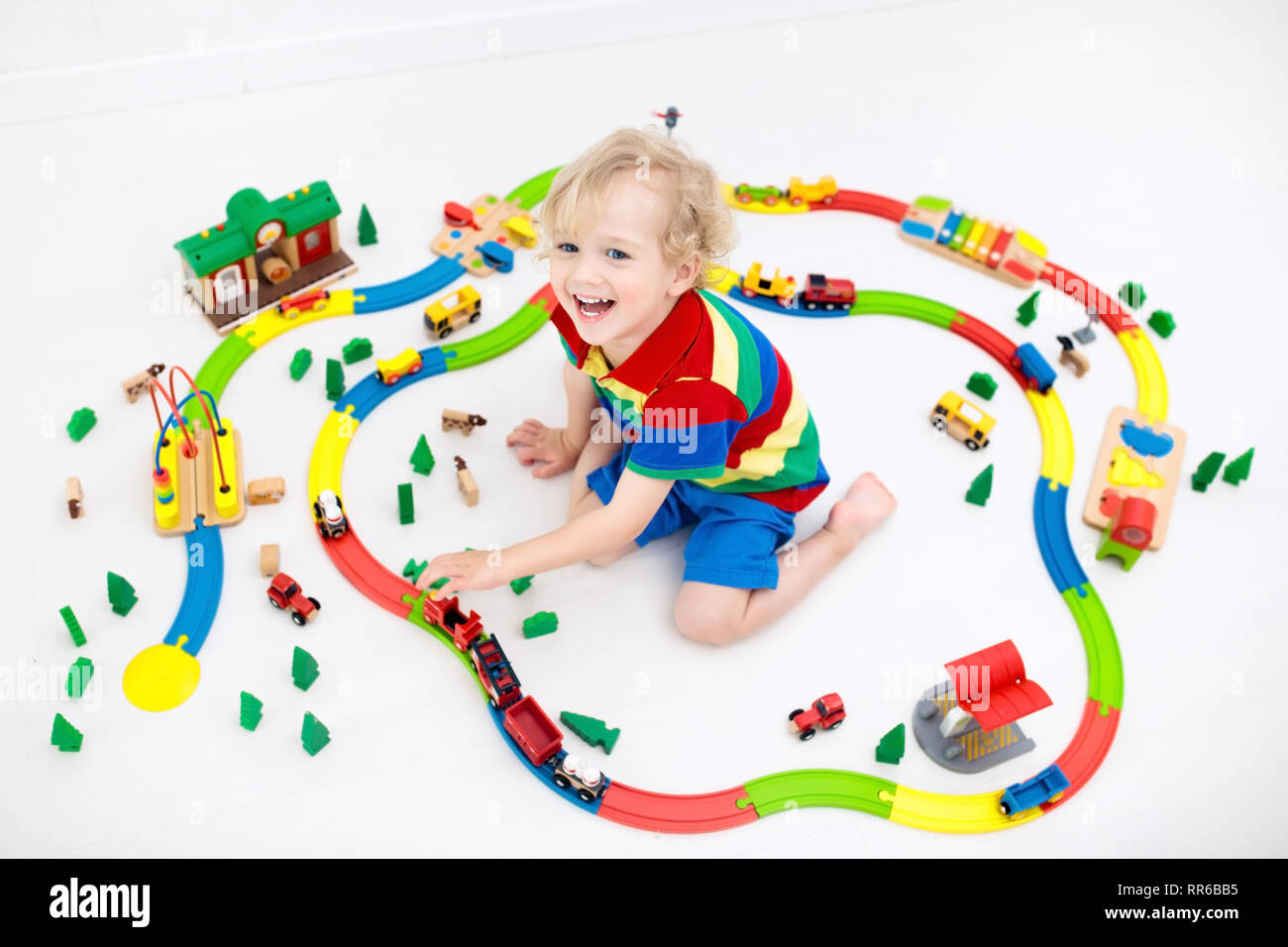 Kids play with toy train railway. Child playing with colorful rainbow ...