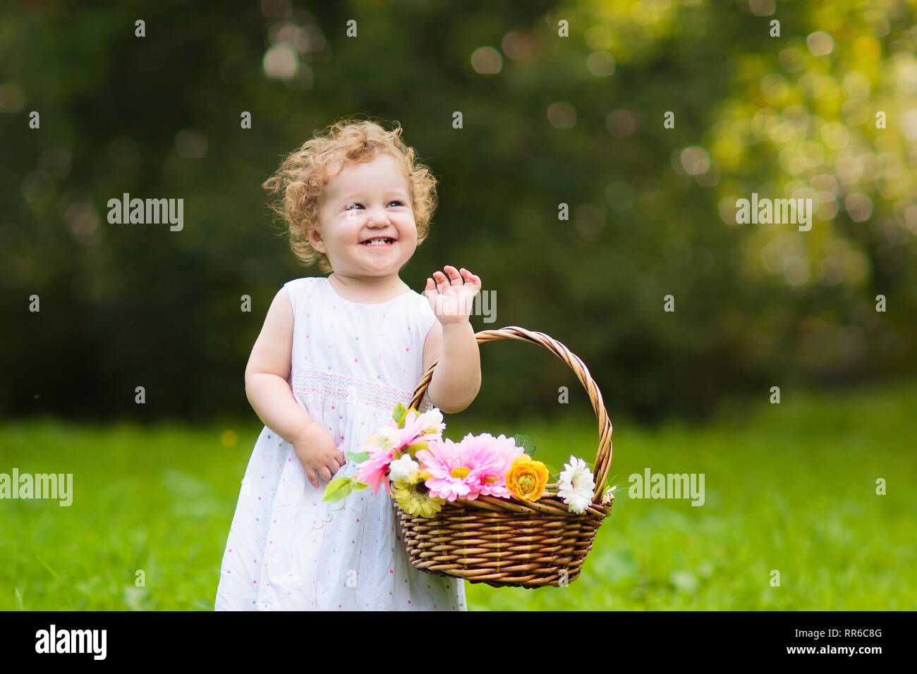 Child with flower basket in sunny park. Little flower girl at wedding ...