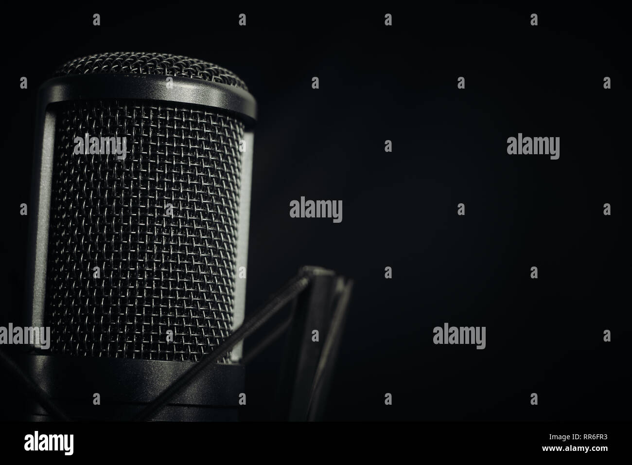 Studio microphone to the left of the frame against a dark background ...