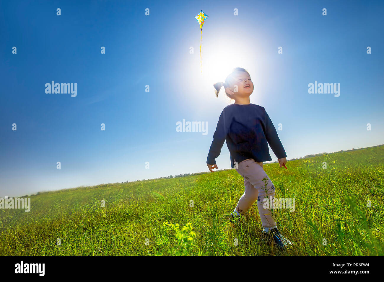 Little girl flying a kite on a green meadow Intentional slope of the ...
