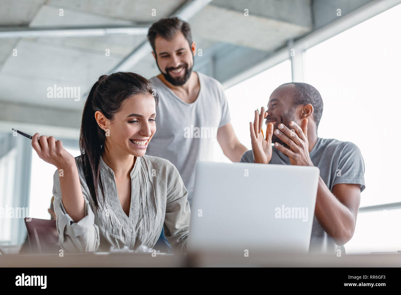 Three diverse business people rejoicing together over a laptop while ...
