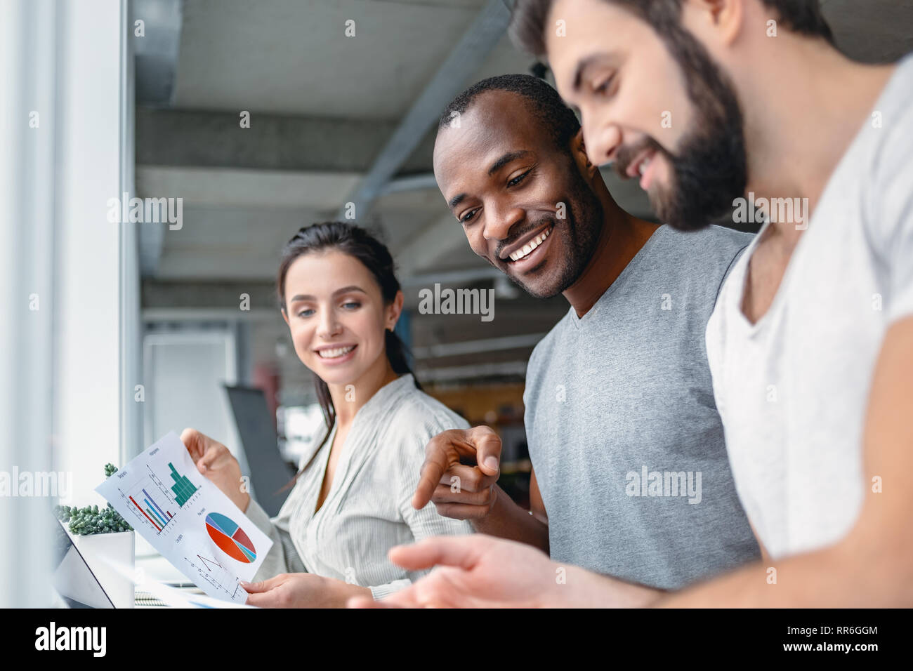 Young co-workers brainstorming in office, men and woman studying chart ...