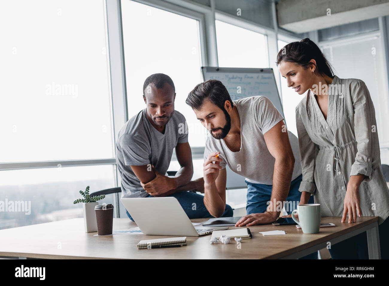 Three diverse business people talking together over a laptop while ...