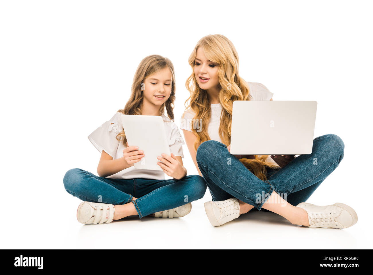 smiling mother and daughter using laptop and digital tablet while ...