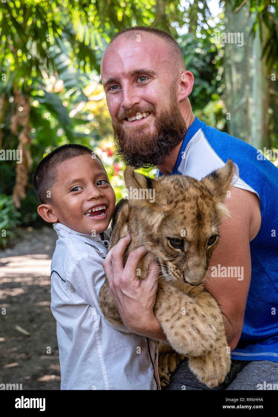 latin child and caucasian man holding baby lion in Guatemalan zoo Stock ...